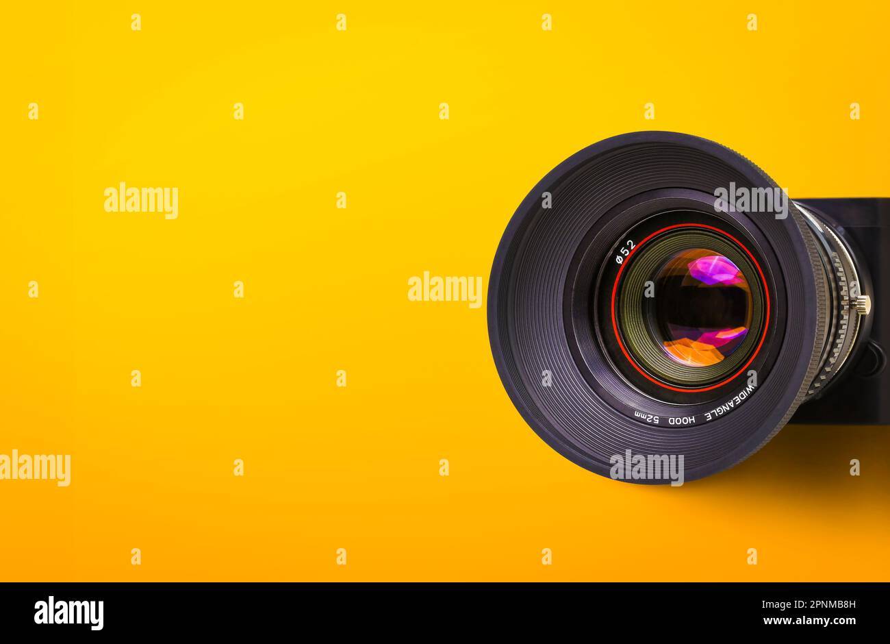 Front lens of vintage film camera with black body isolated on yellow or ...