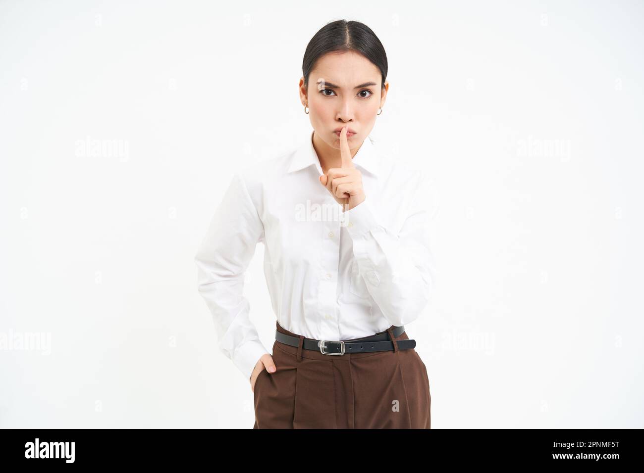 Strict and serious businesswoman shushing, puts finger on lips, tells ...