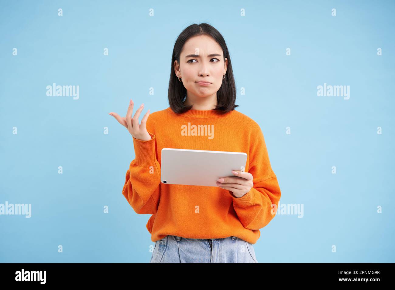 Woman with digital tablet, looks confused, cant understand smth on her ...