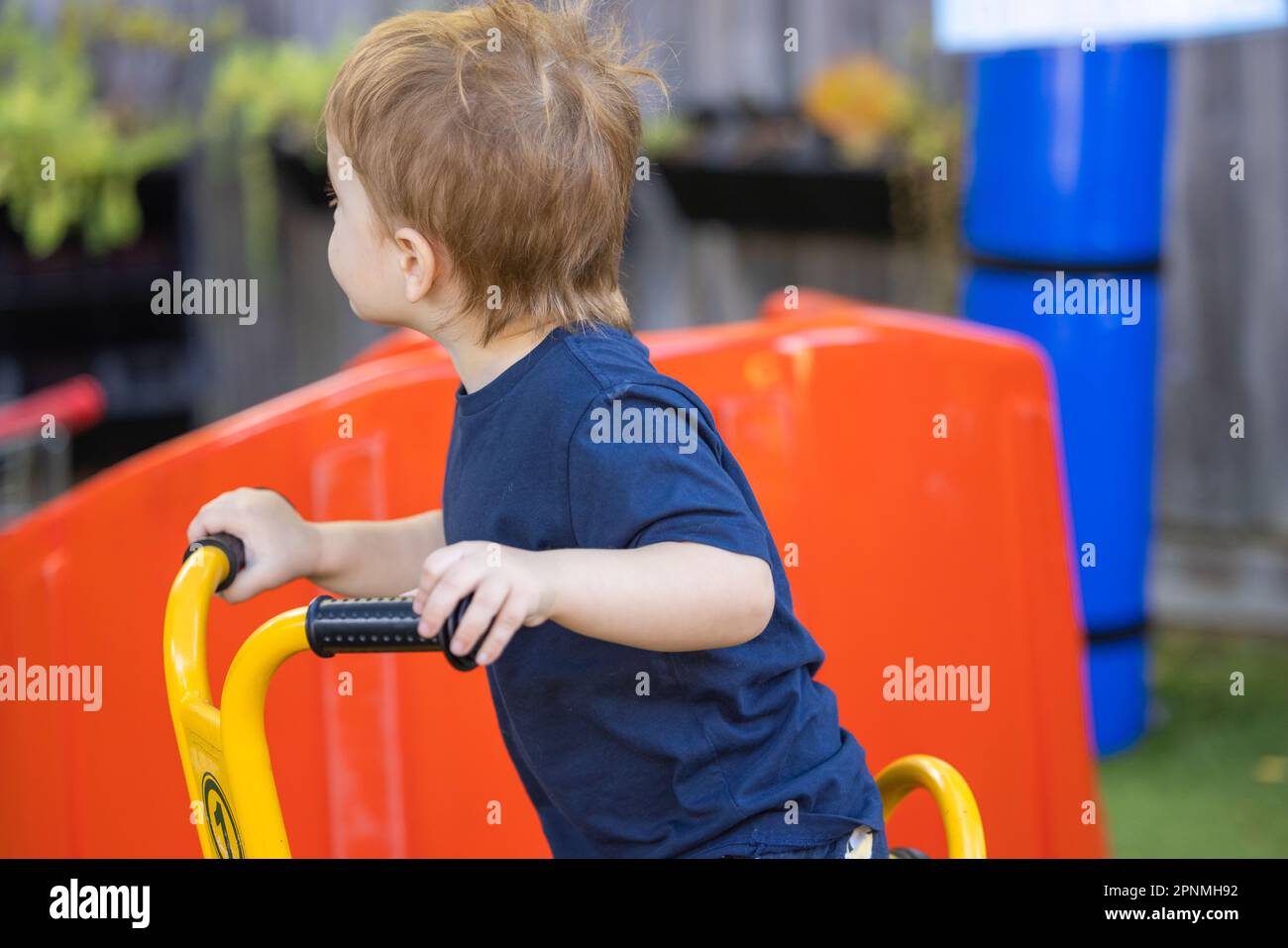 Preschool age child riding bike in a vibrant fun outdoor kindergarten yard Stock Photo - Alamy