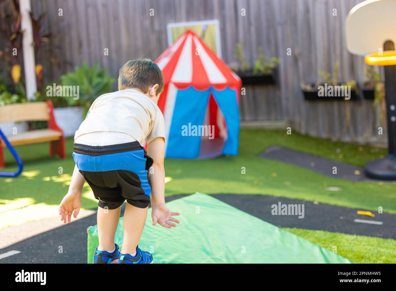 Preschool age child playing in a vibrant fun outdoor kindergarten yard ...