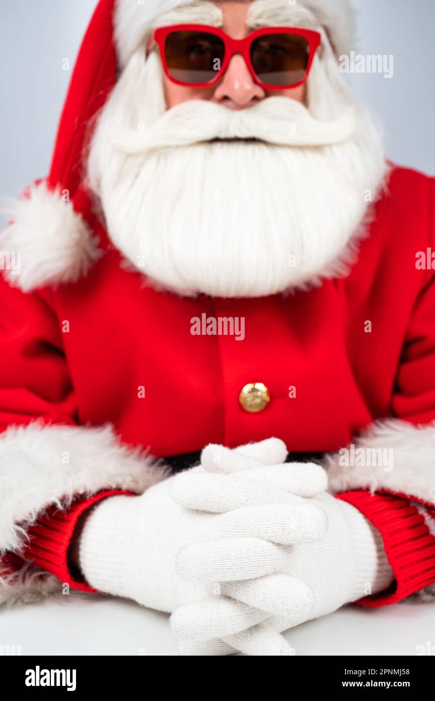 Portrait of santa claus sitting with his arms folded at a white table ...