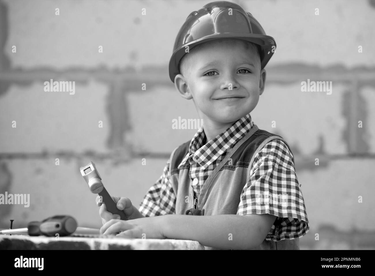 Cute little kid in builder helmet with repair tools on construction ...