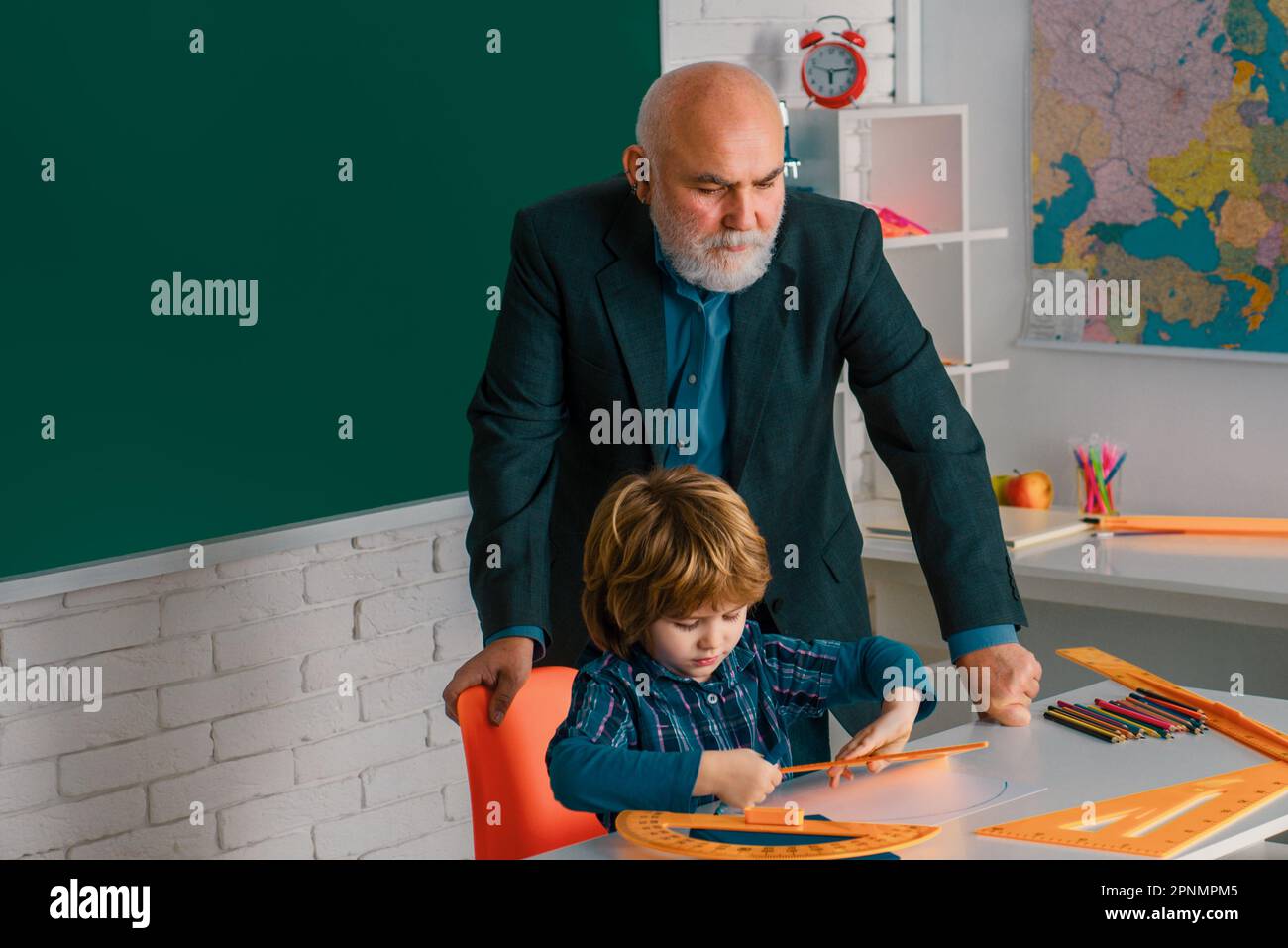 Educational process. Elementary school teacher giving female pupil ...