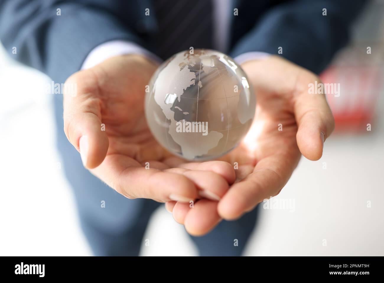 Man in business suit holds glass globe with continents Stock Photo - Alamy