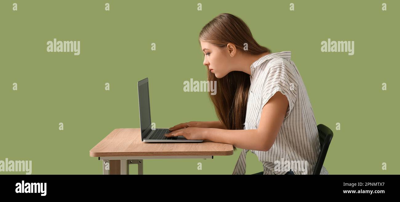 Teenage girl with bad posture using laptop while sitting at table ...