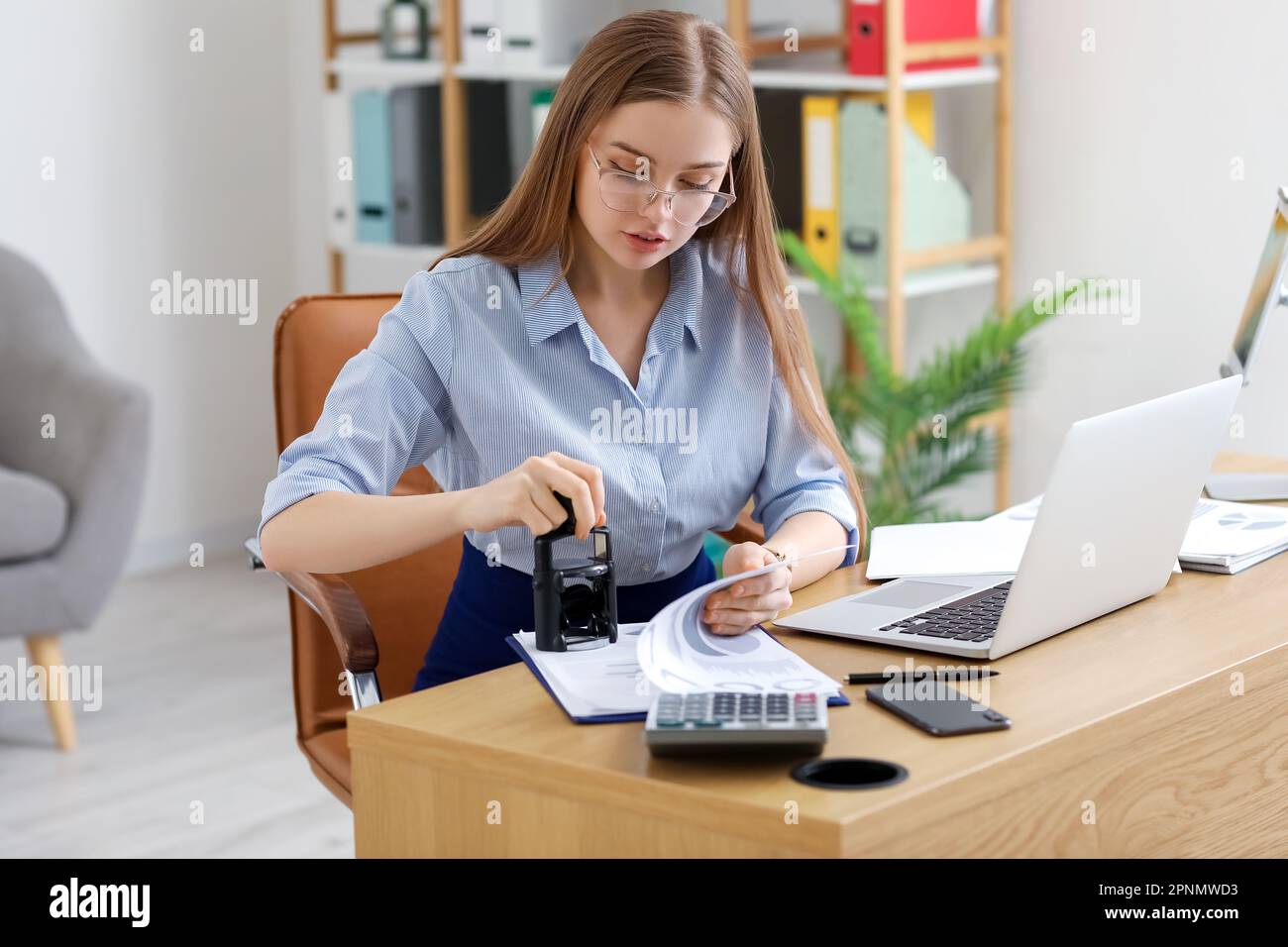 Female accountant stamping document at table in office Stock Photo - Alamy