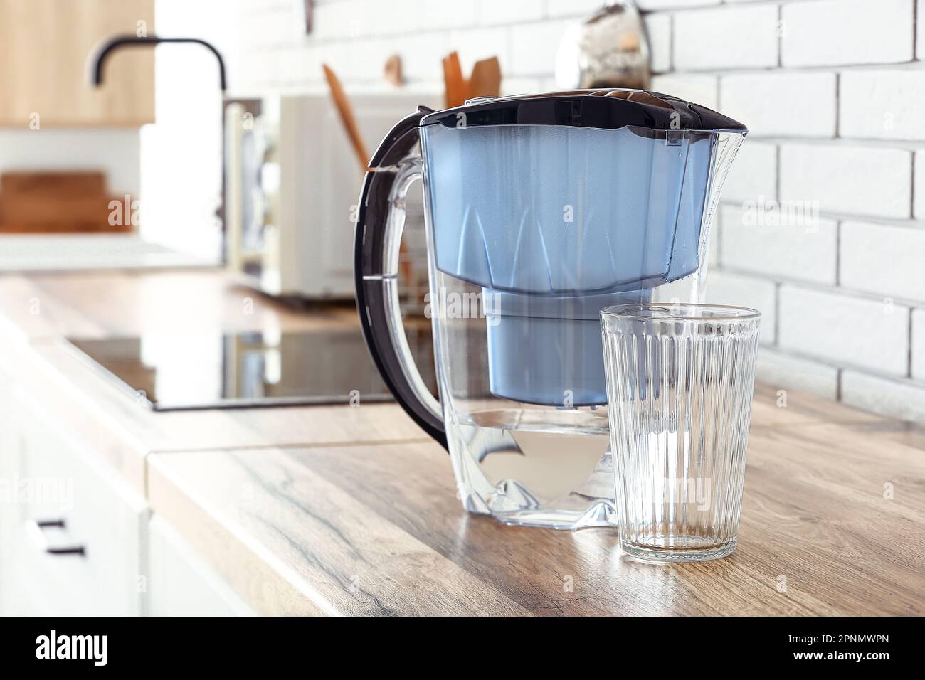 Modern filter jug and glass of water on kitchen counter Stock Photo - Alamy