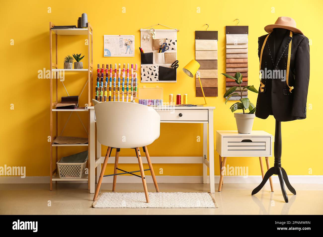 Interior of stylish atelier with tailor's workplace, fabric samples and ...