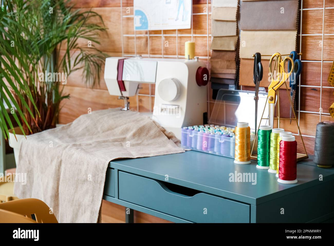 Tailor's workplace with sewing machine, fabric and thread spools in ...
