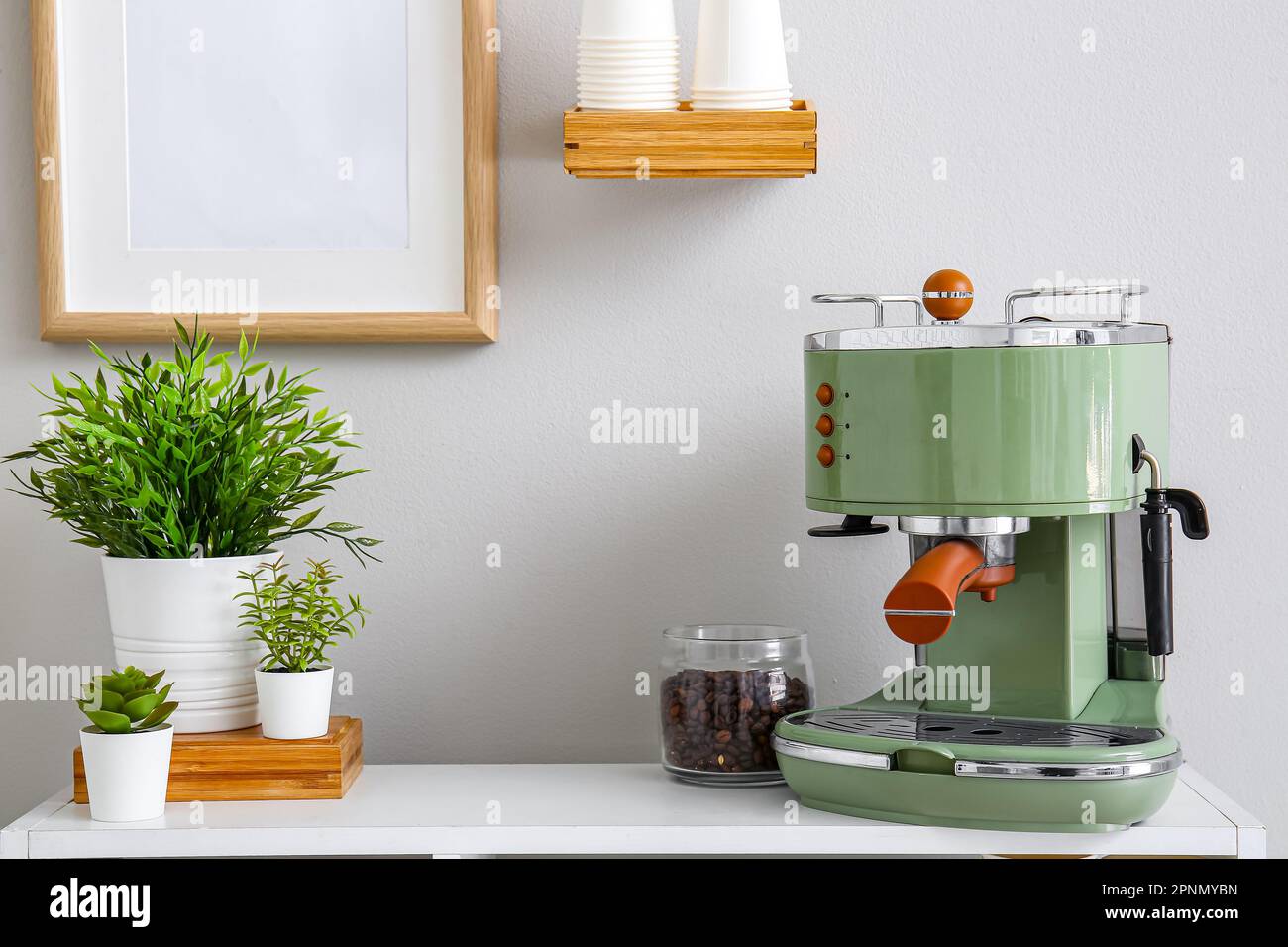 Modern coffee machine, jar with beans and houseplants on table near ...