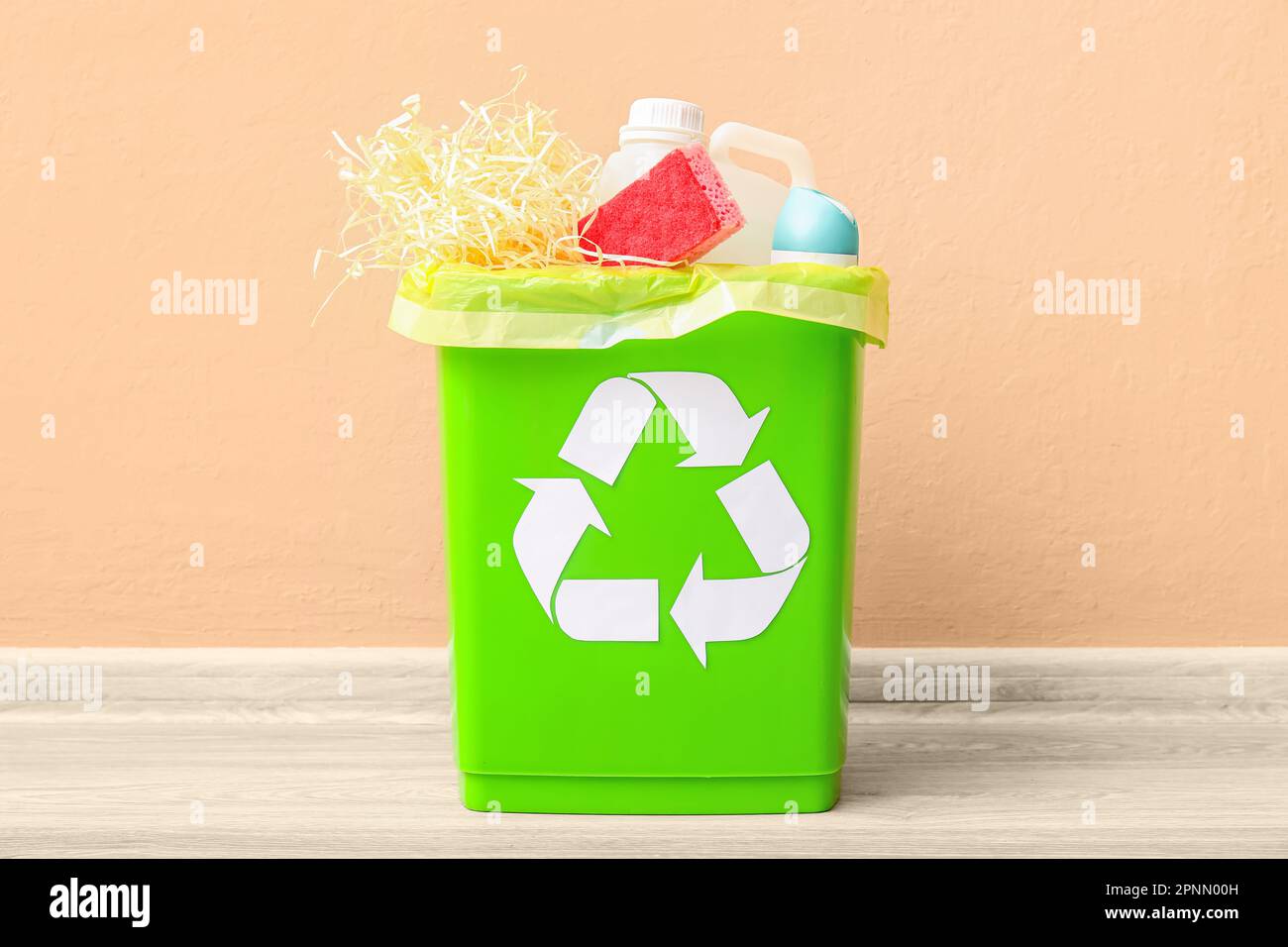 Trash bin with different garbage near beige wall Stock Photo - Alamy