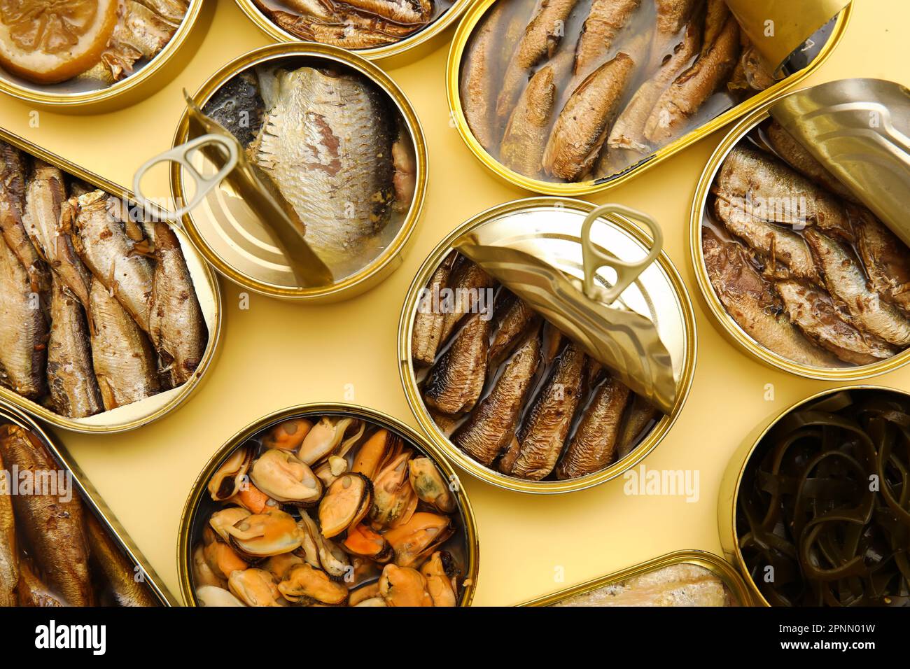 Many opened tin cans with different fish on beige background Stock ...