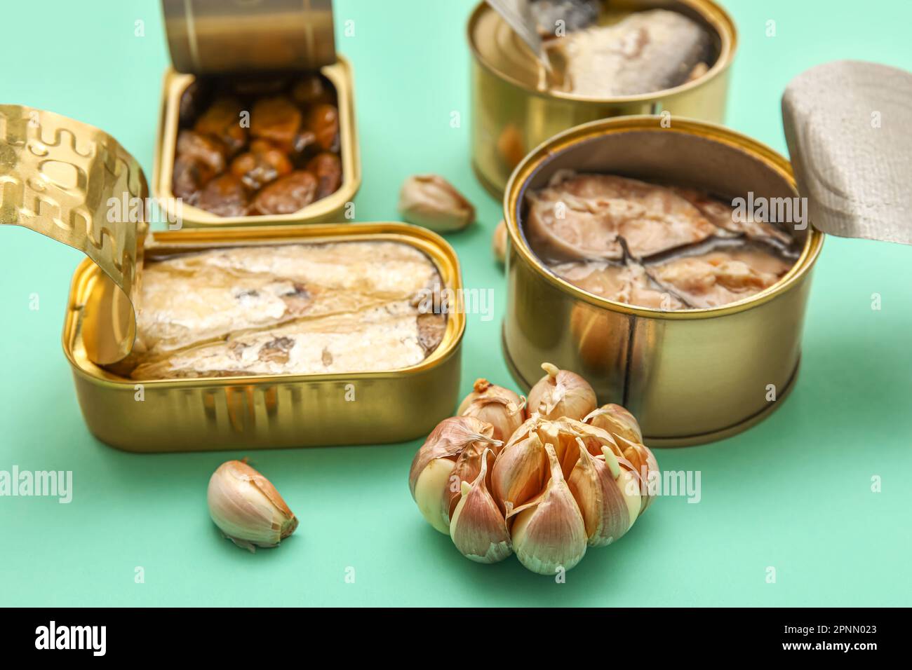 Opened tin cans with different fish and mussels on turquoise background ...