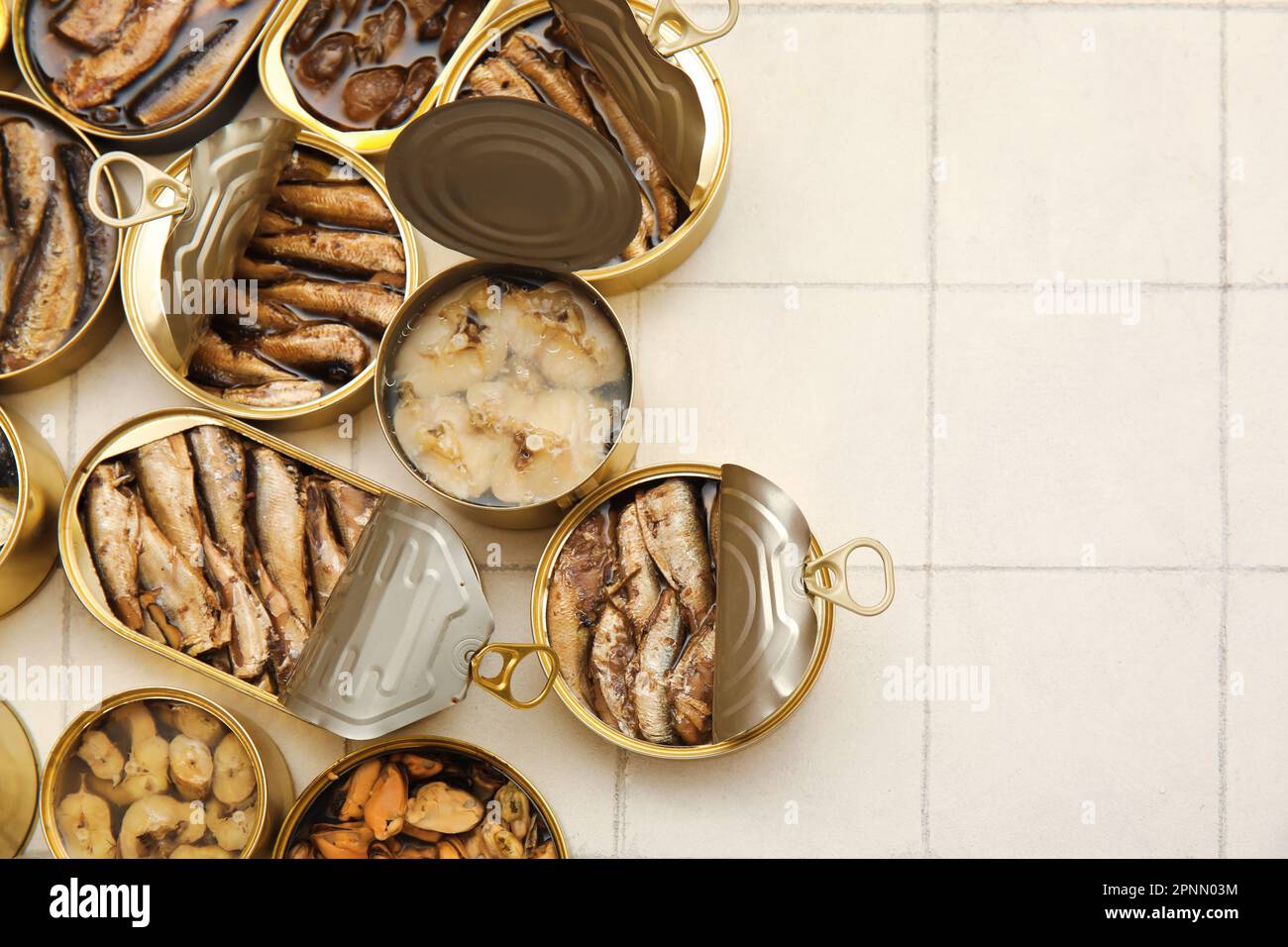 Many opened cans with different fish on tiled table, closeup Stock ...