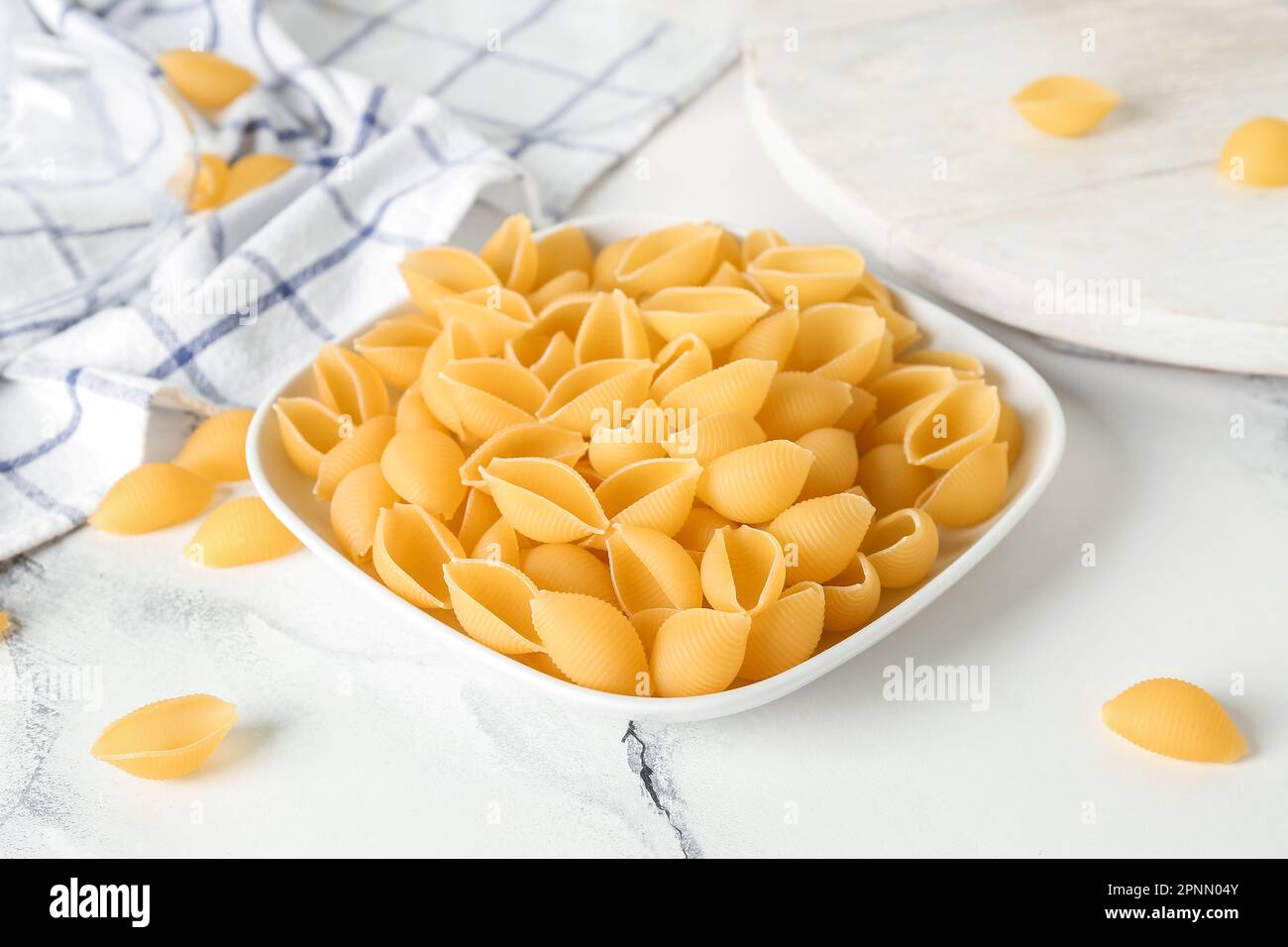 Plate with raw conchiglie pasta on white marble background Stock Photo ...