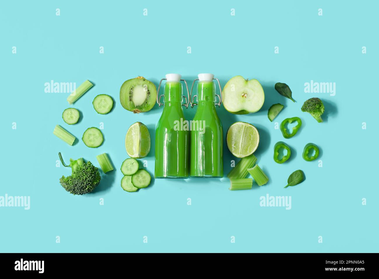 Glass bottles of tasty green juice and ingredients on turquoise ...