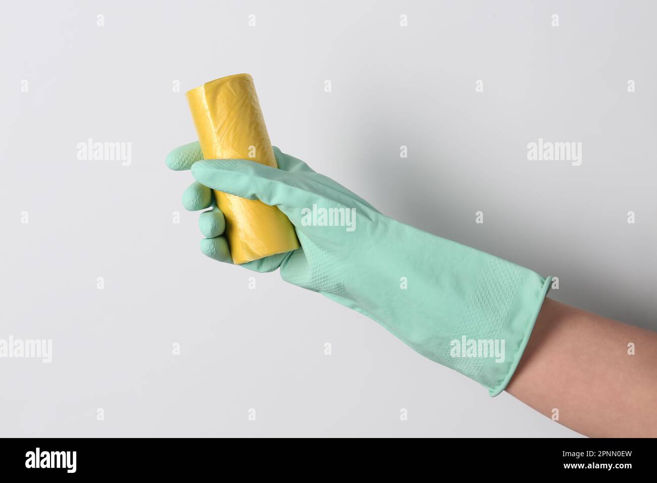 Hand in rubber glove with roll of garbage bags on white background ...