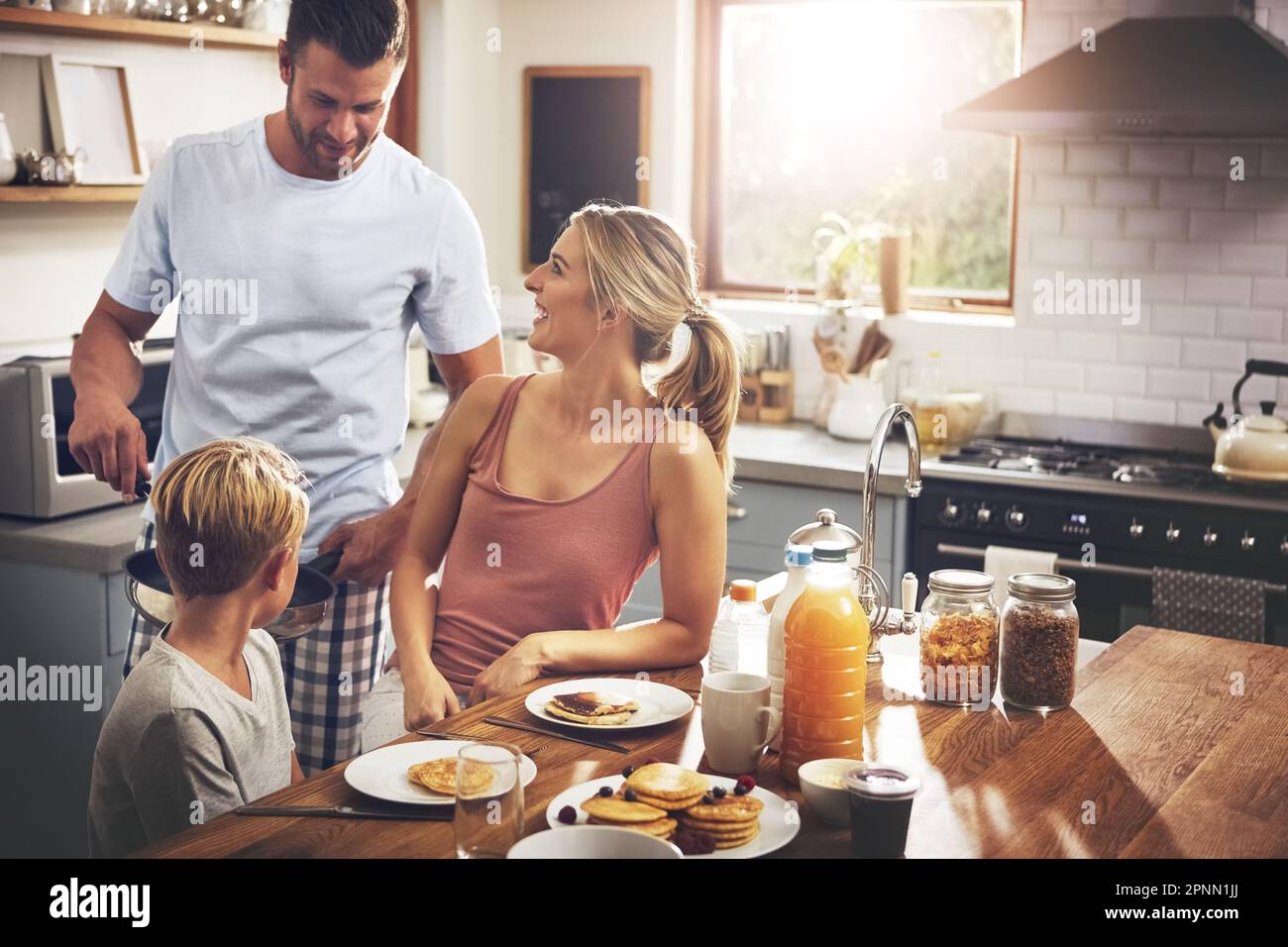 Dad is taking care of breakfast. a little boy eating breakfast with his ...