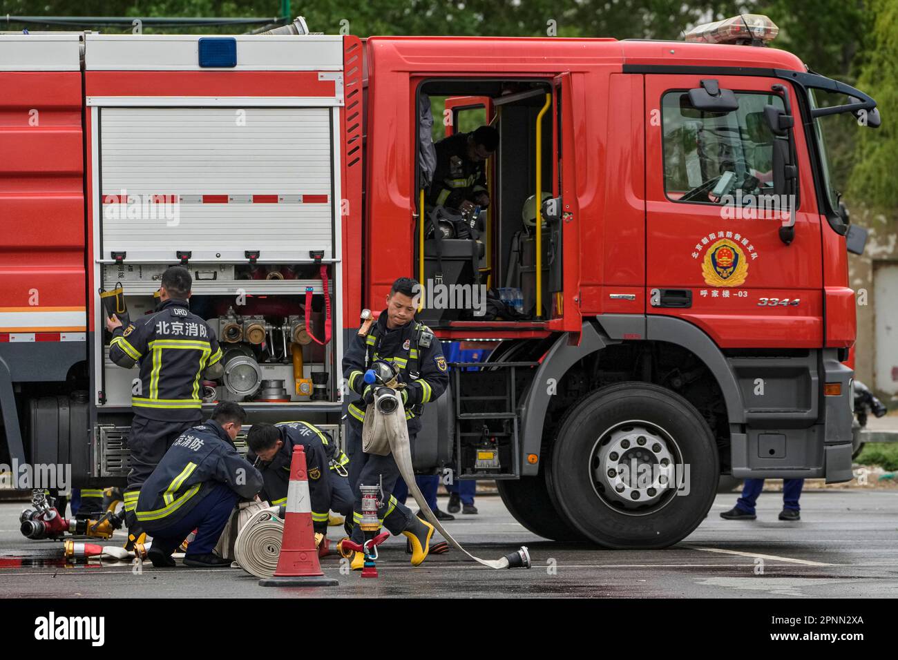 Firefighters load fire hoses near a fire truck after conducting a fire ...