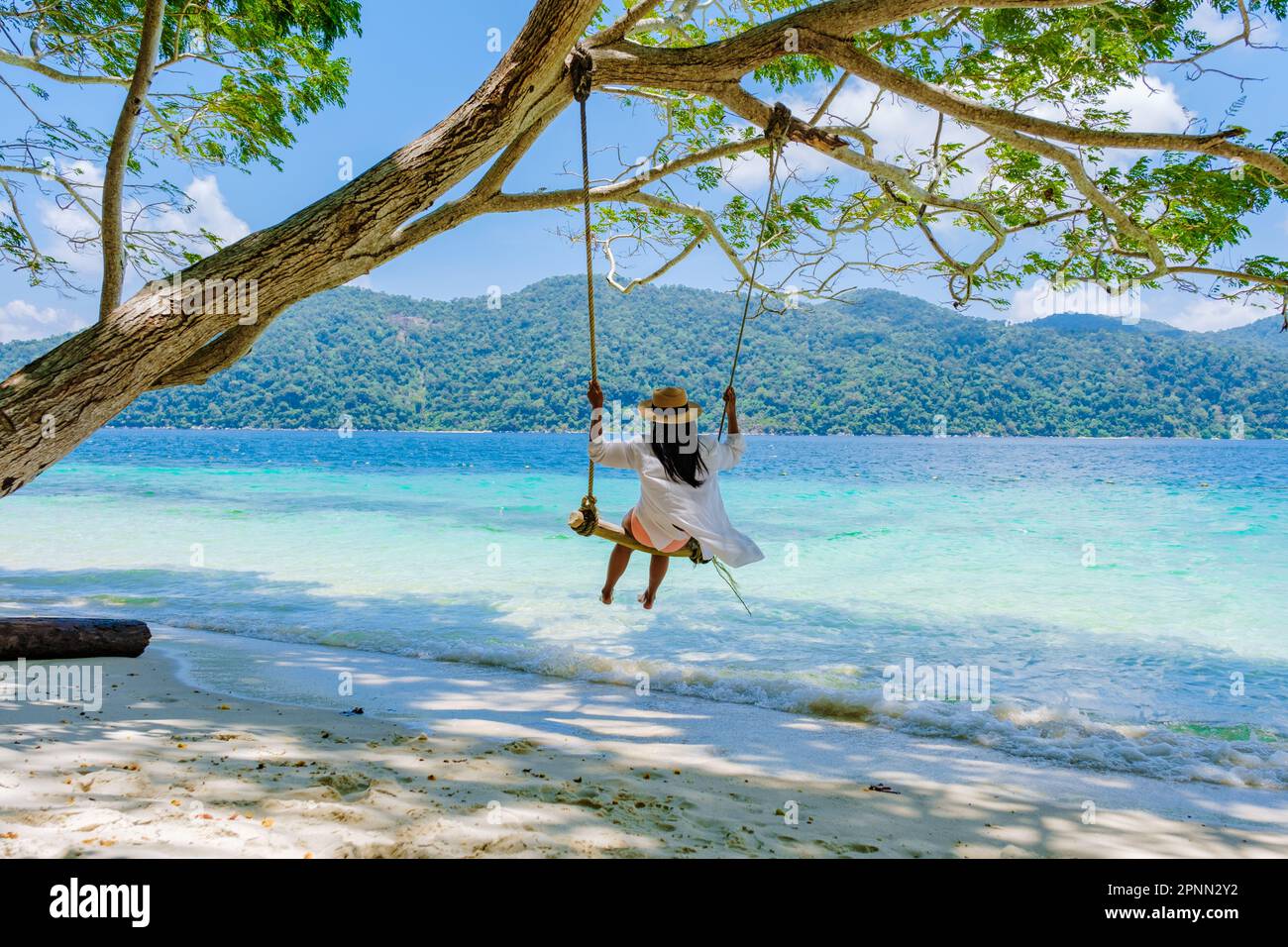 woman swinging around under a tree at a swing on the beach of Koh Lipe ...