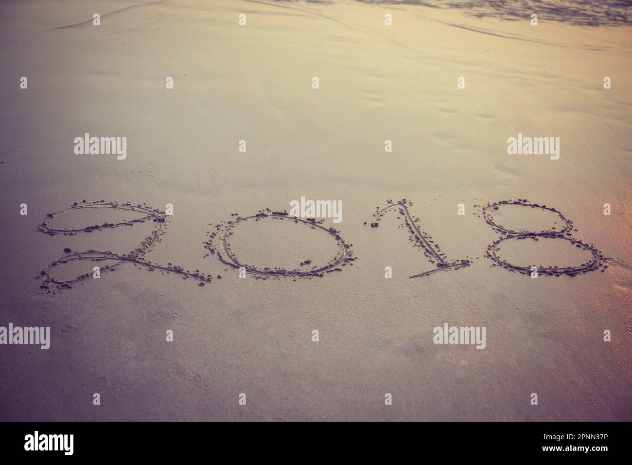 Numbers 2018 handwritten on sand at the beach during sunset time ...