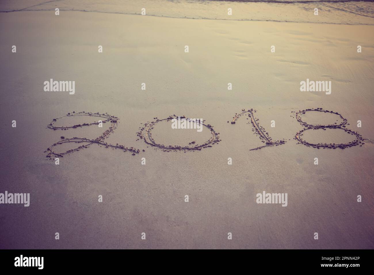 Numbers 2018 handwritten on sand at the beach during sunset time ...