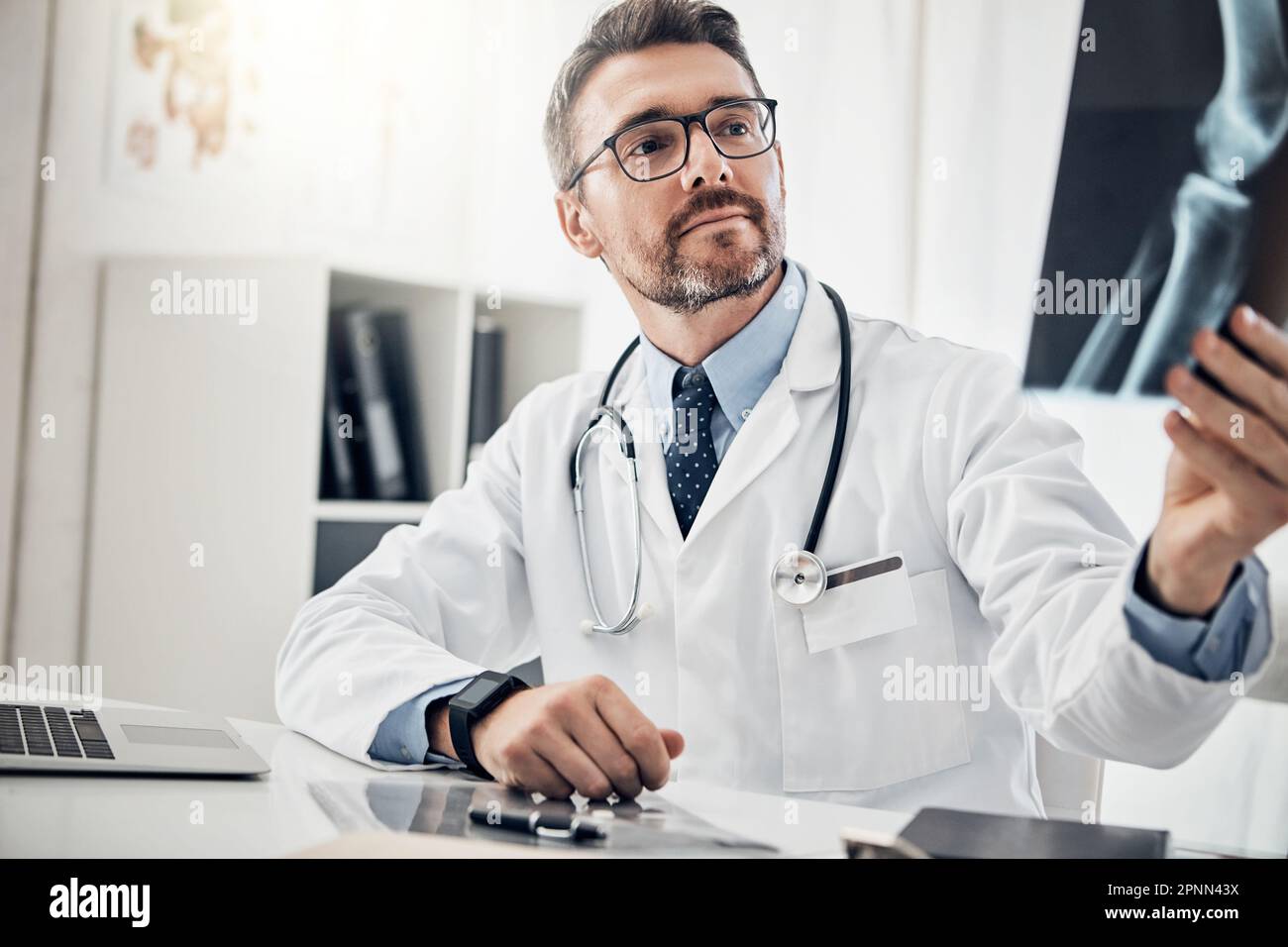 Identifying the root of the problem. a focused doctor looking at an x ...