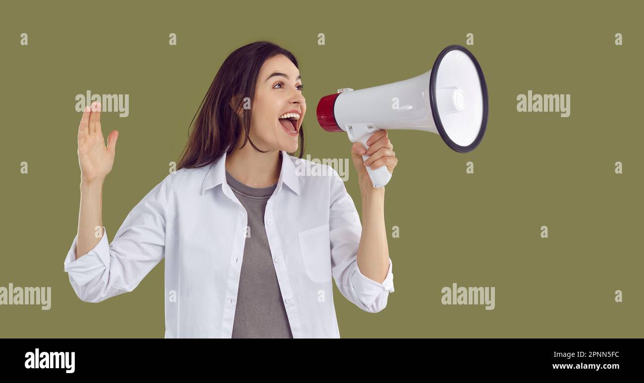Excited young woman advertising something and screaming loudly through ...