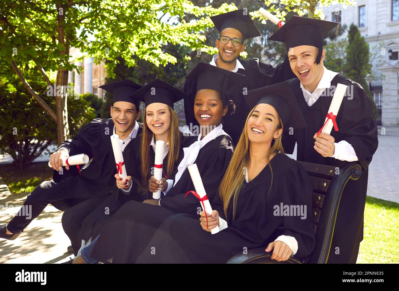 Group of laughing multicultural people in graduation gowns and caps ...