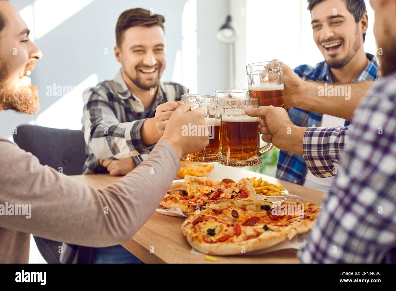 Group of male close friends eating pizza and drinking beer Stock Photo ...