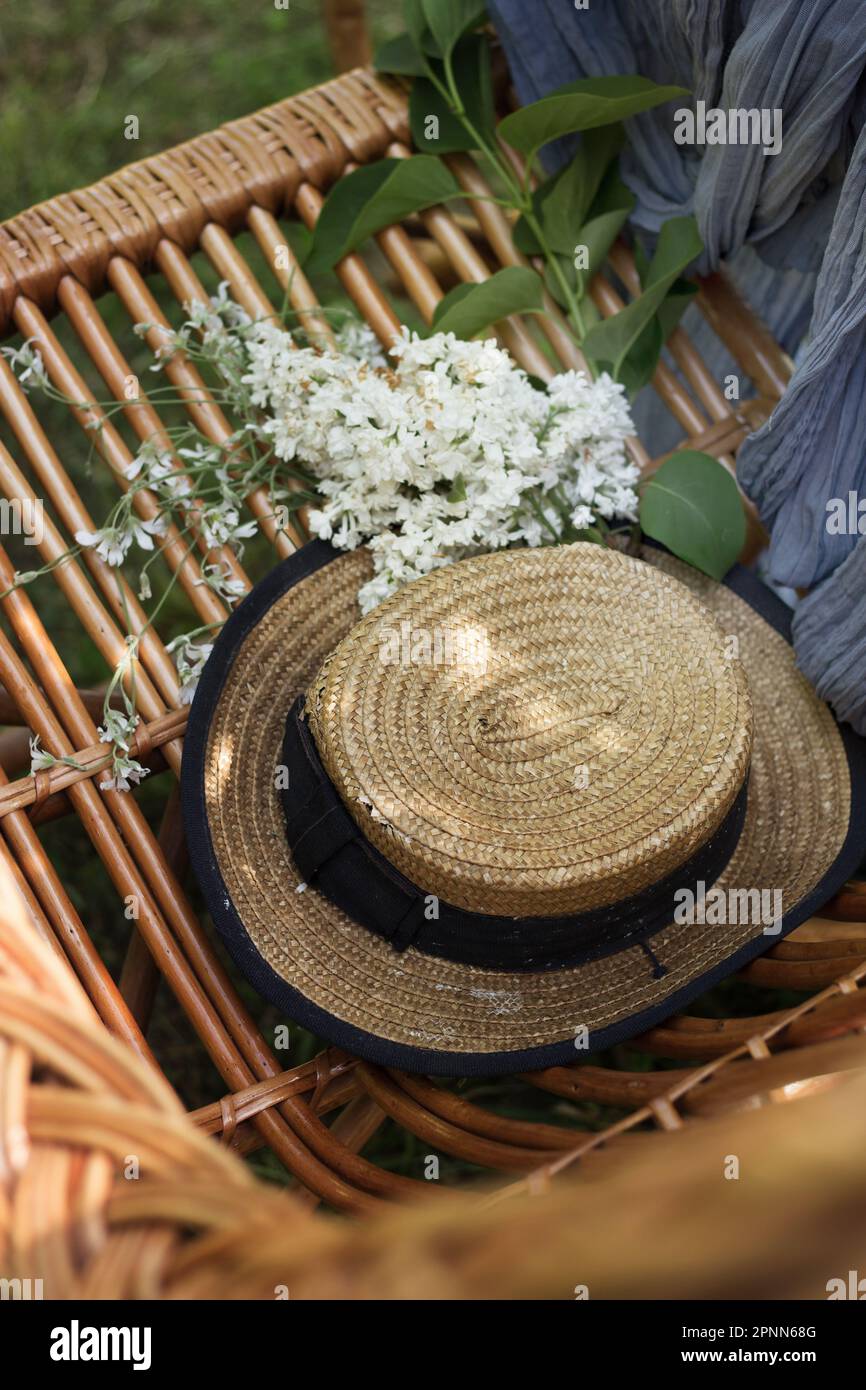 Slow life. A straw hat with flowers lies on a wicker chair. View from ...