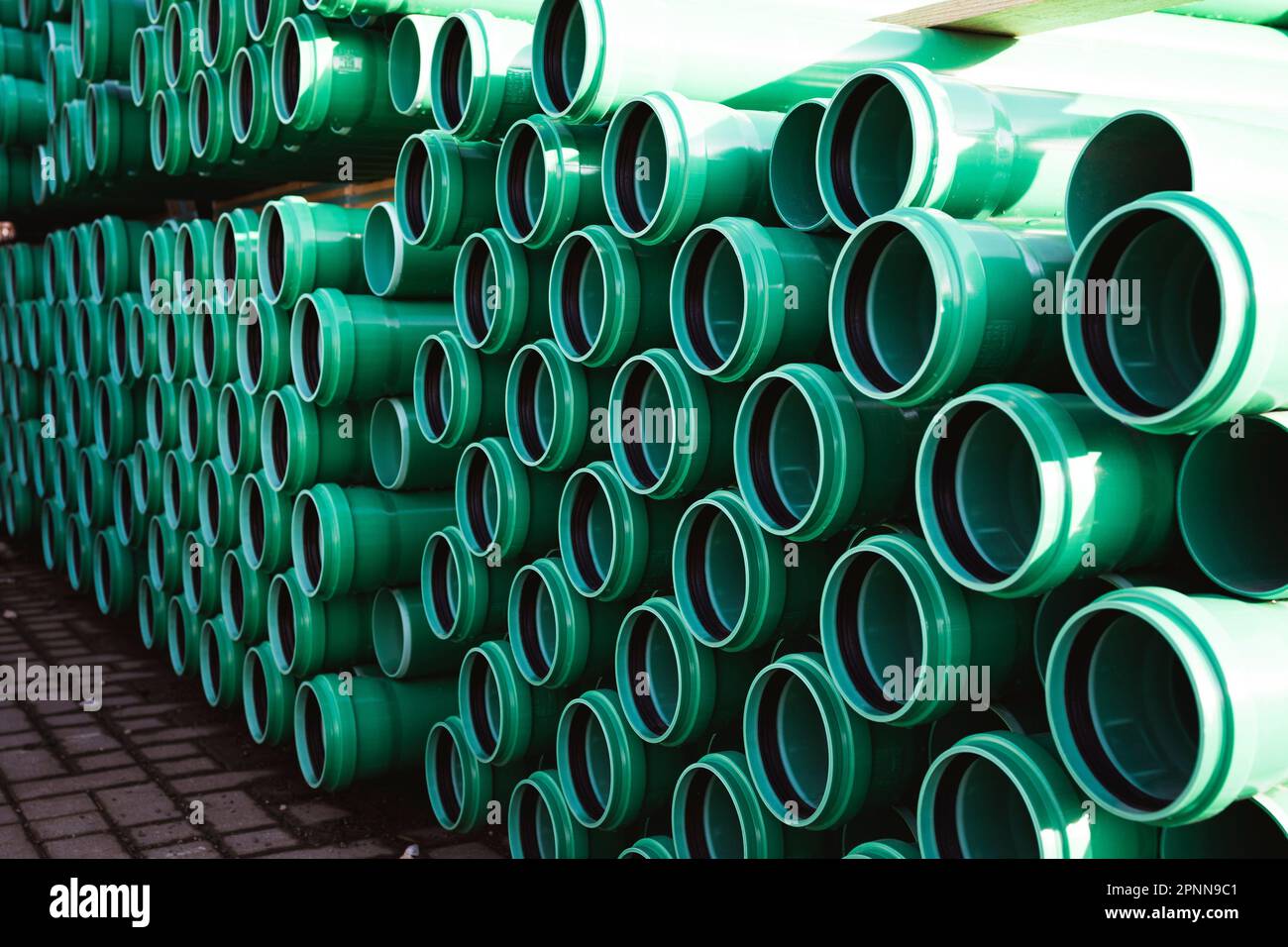 A large array of green industrial pipes are arranged in a neat pile and ...