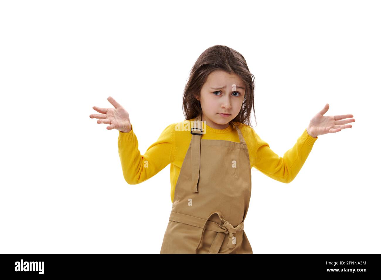 Amazed little child girl in beige chef's apron, asking questions ...
