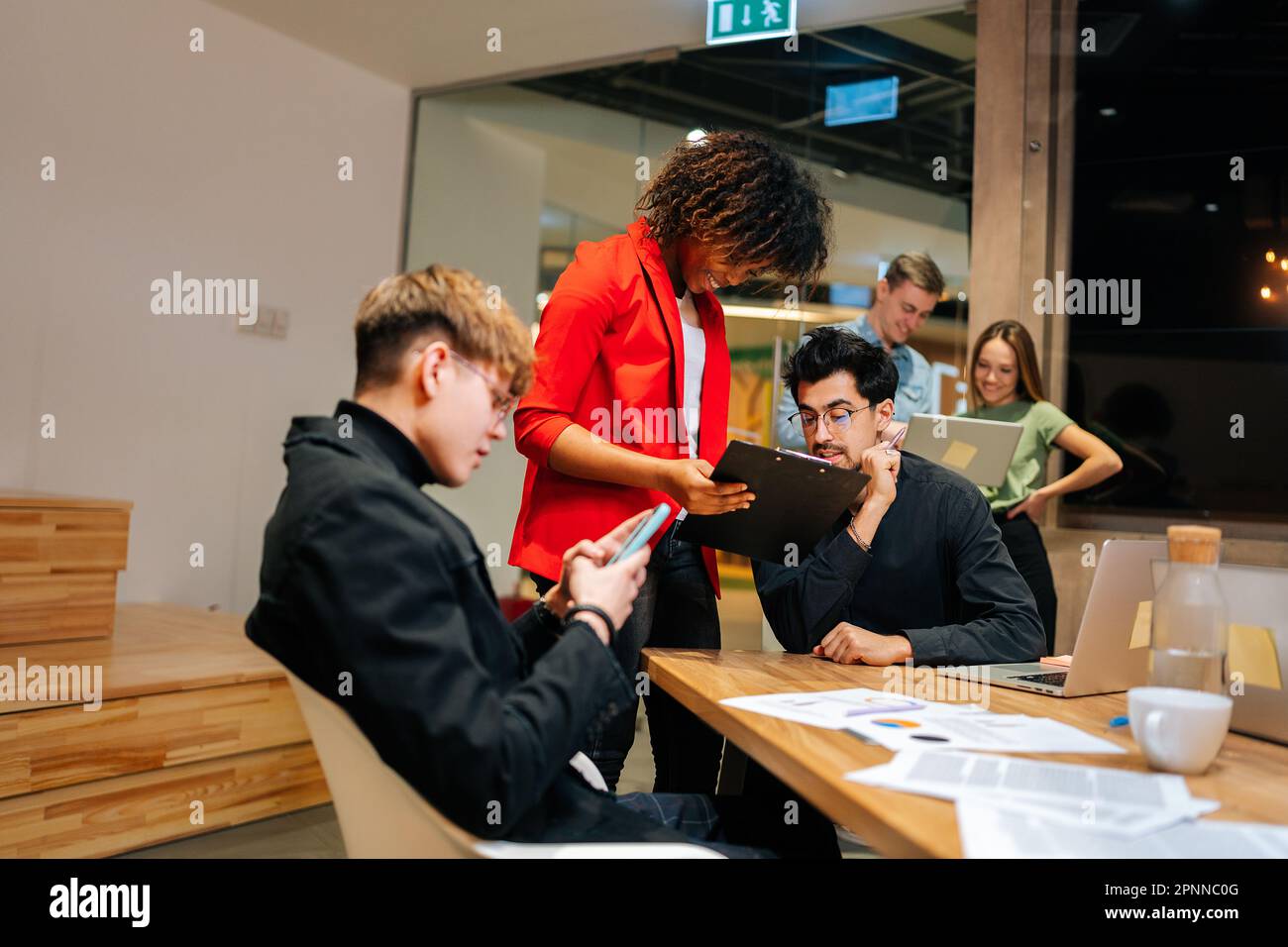 Professional male team leader checking document to cheerful African ...