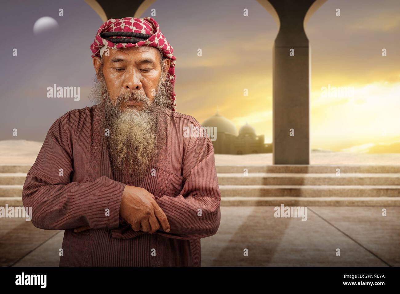 Muslim man with a beard wearing keffiyeh with agal in praying position ...