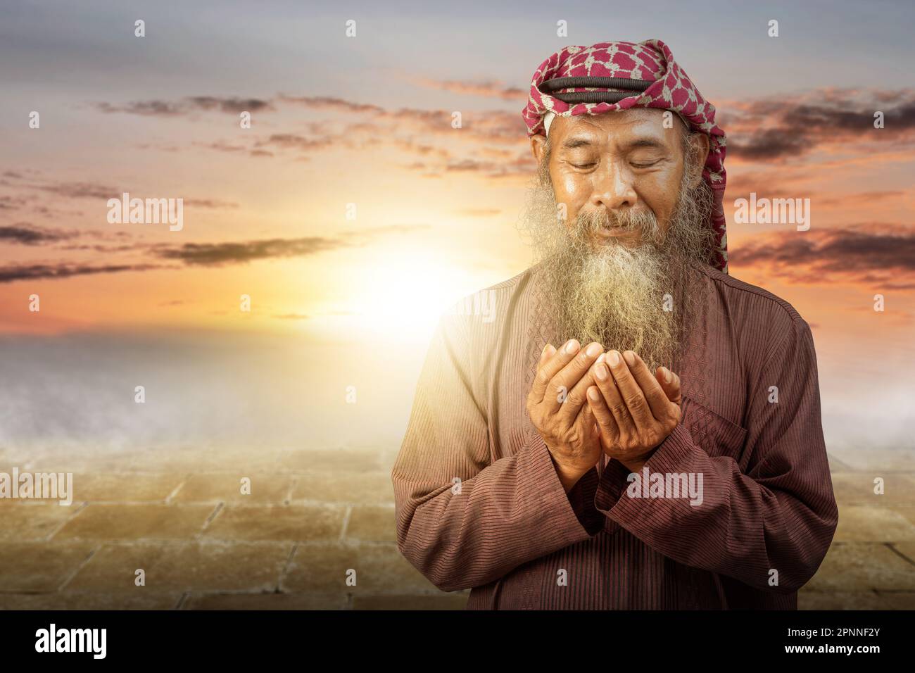 Muslim man with a beard wearing keffiyeh with agal in praying while ...