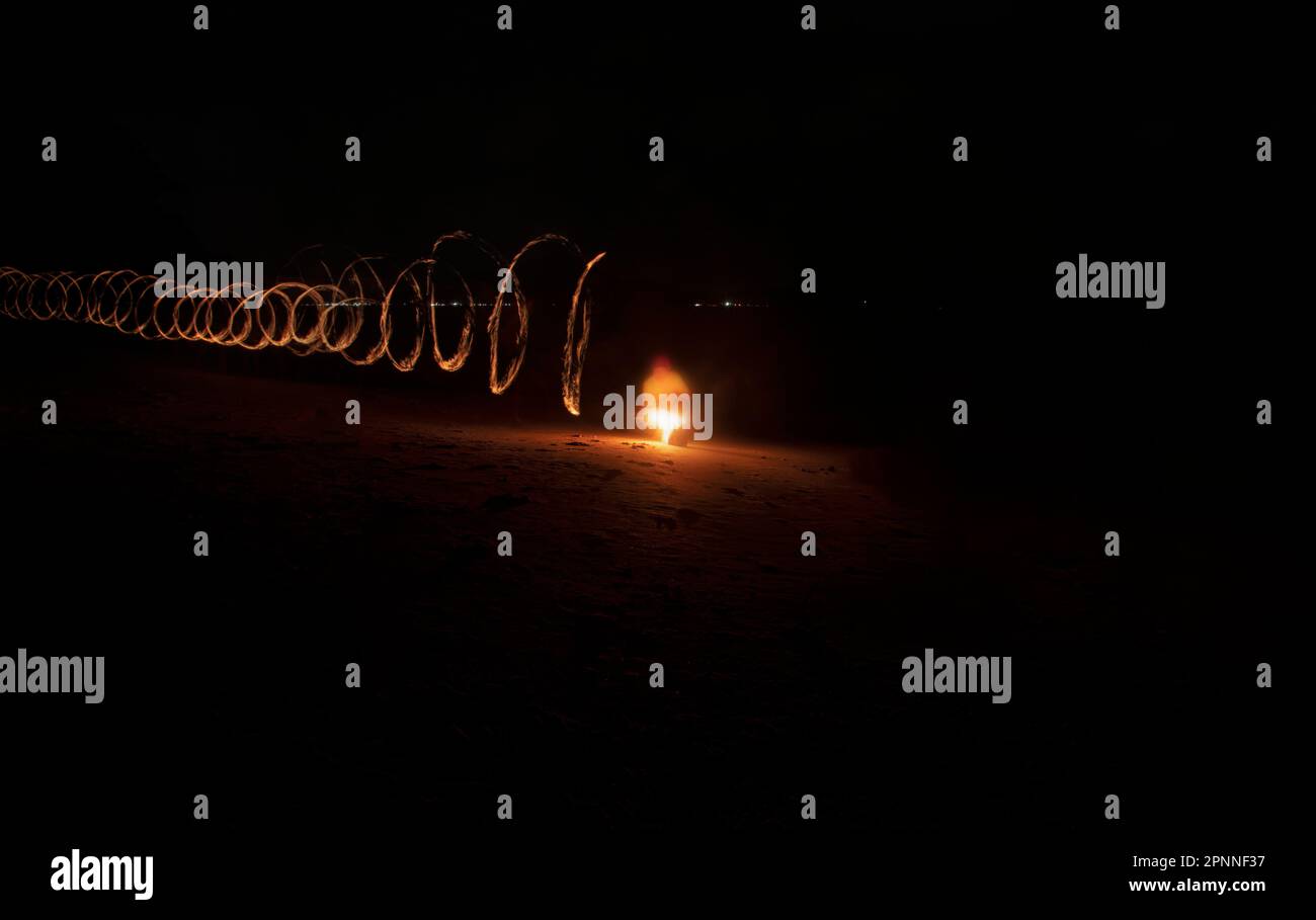 rotating circle of fiery flame moving towards the man squatting in the ...