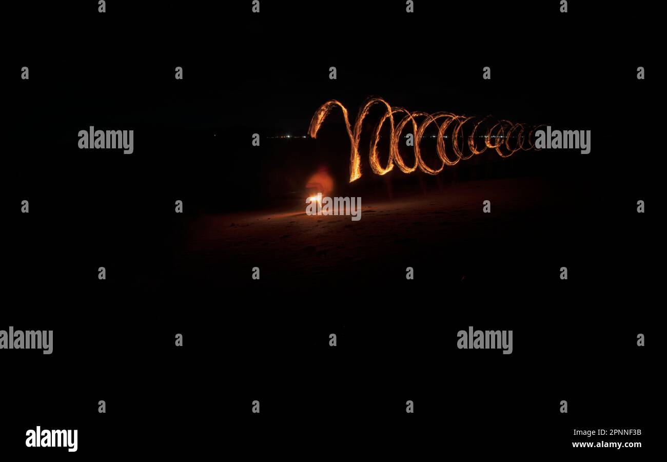 rotating circle of fiery flame moving towards the man squatting in the ...