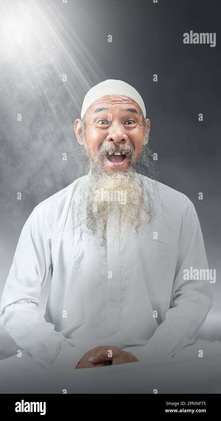 Muslim man with a beard wearing a white cap with bright light ...