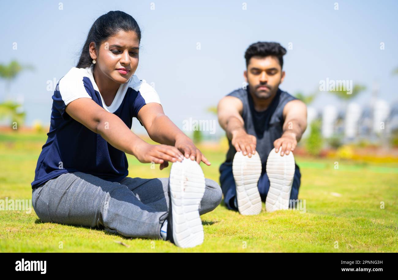serious Young Indian people doing stretching exercise by touching feet ...