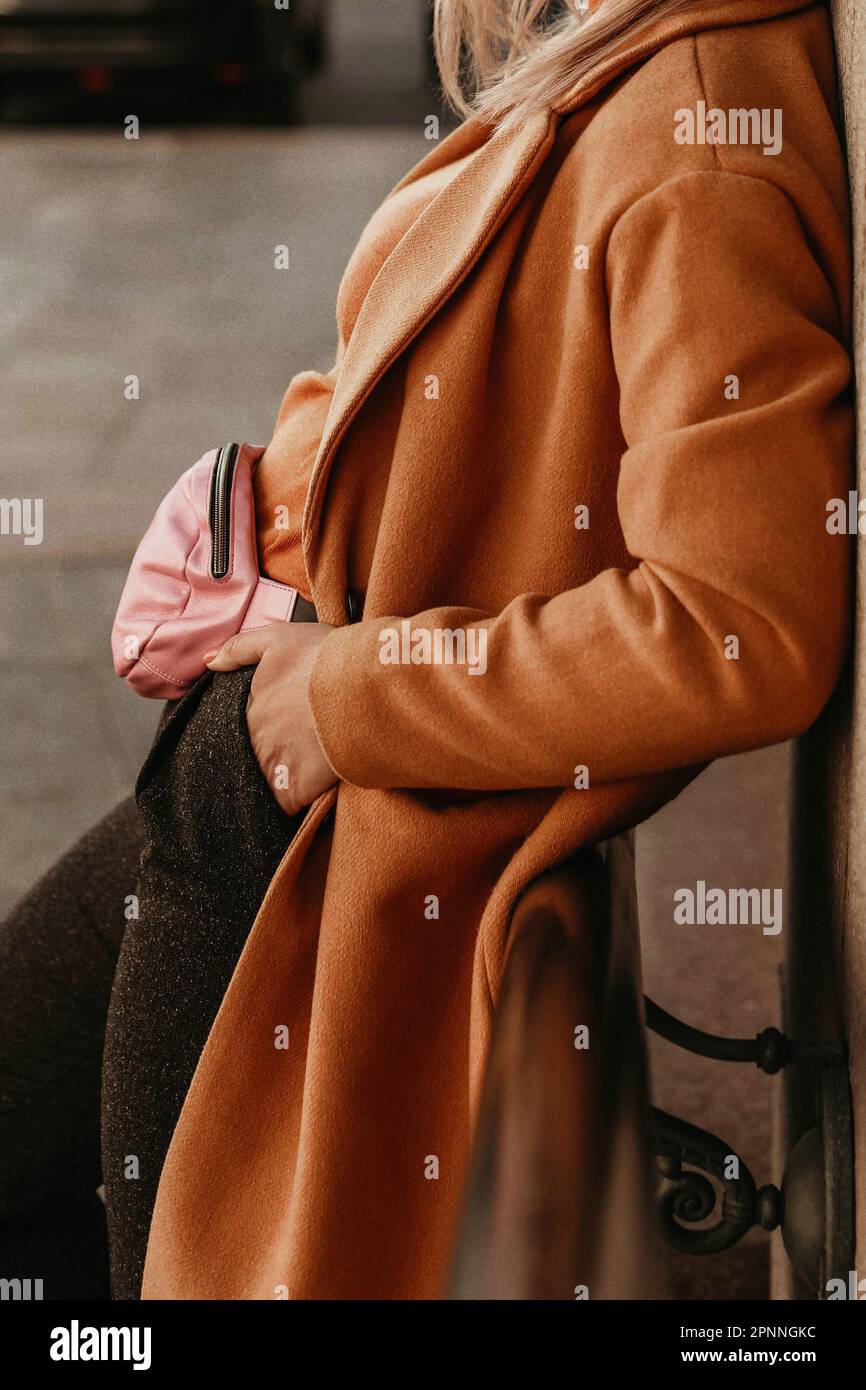 Female body cropped head in the orange warm cozy coat. Outdoor portrait ...