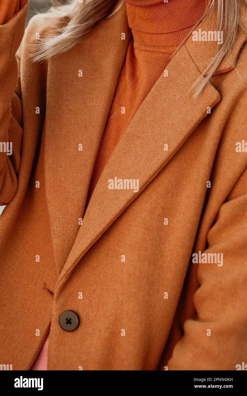 Details of orange warm cozy female sweater and coat. Outdoor portrait ...