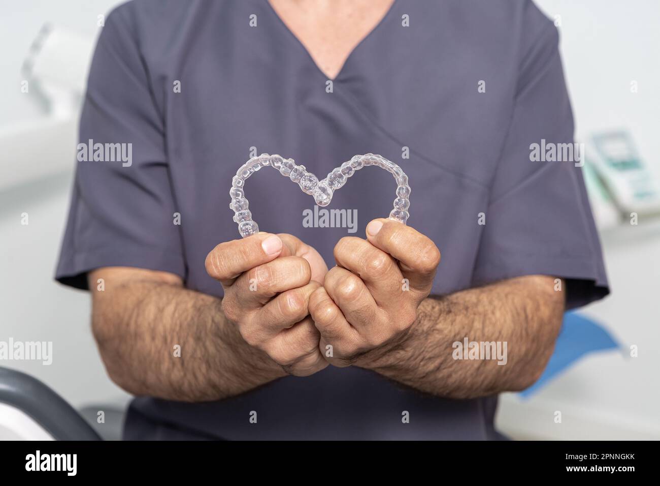 Crop unrecognizable male dentist in uniform making heart shape with ...