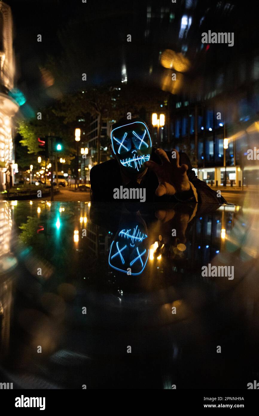 Purge mask, man in a suit with LED mask. At night, city lights ...