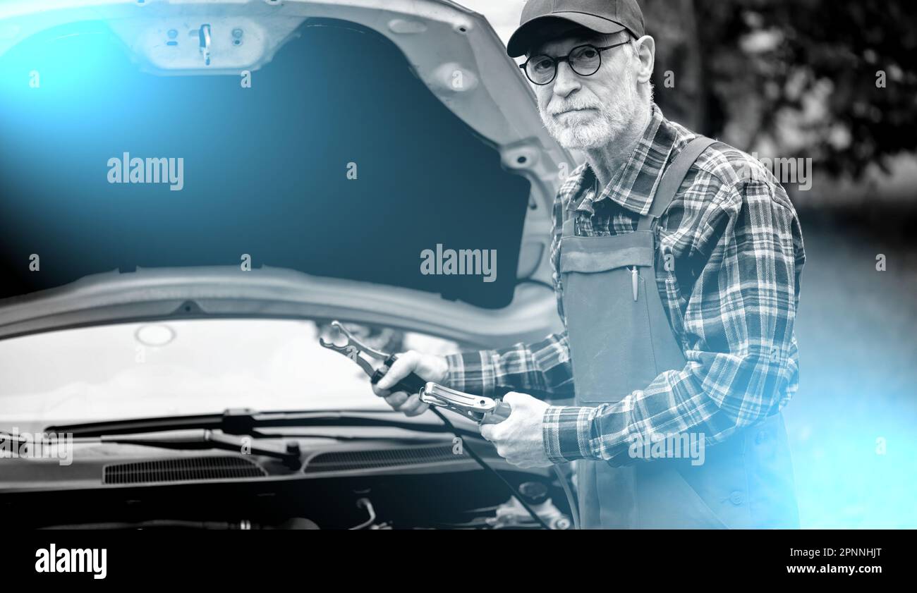 Car mechanic using cables to start a car engine; light effect Stock ...