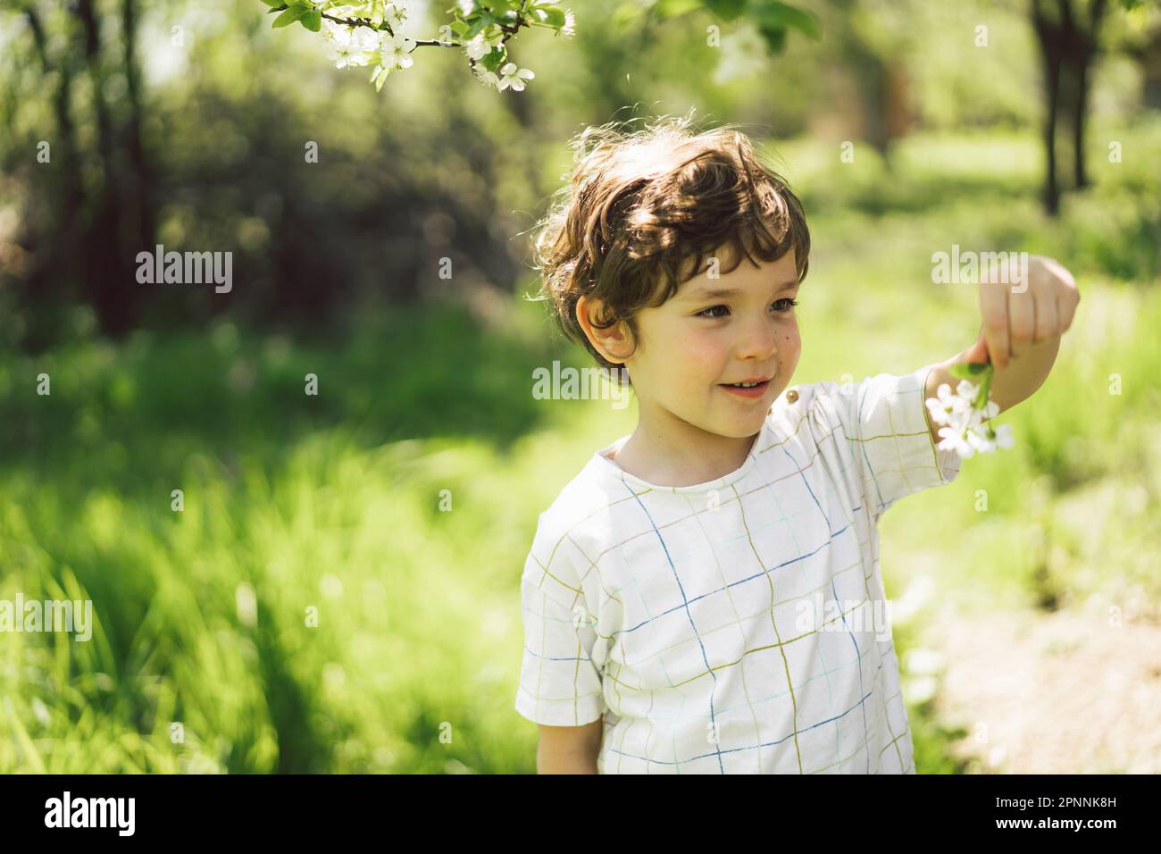 Happy little boy walking in spring garden Stock Photo - Alamy