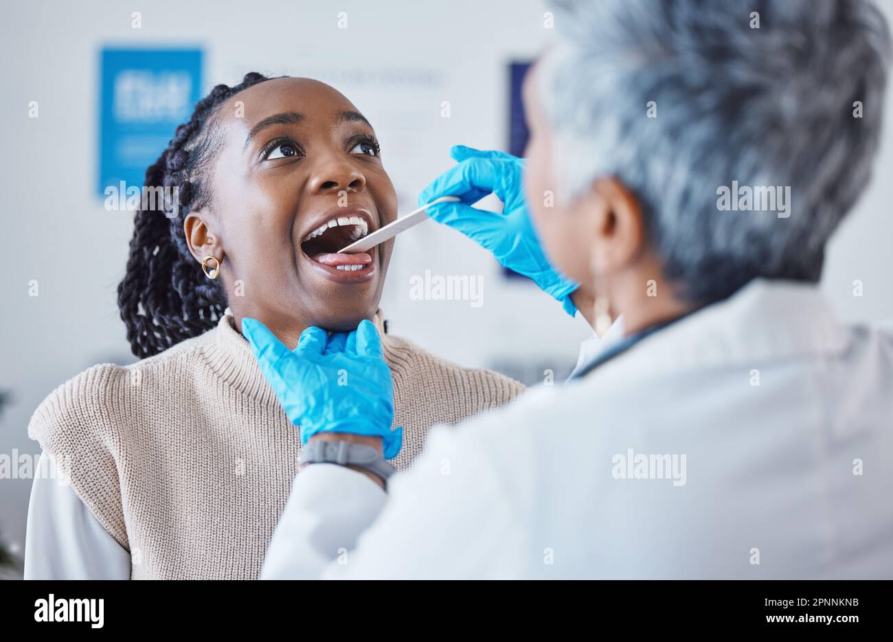 Consultation, doctor and patient with tongue depressor, open mouth pain ...