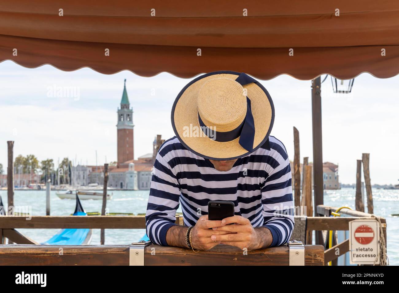 Gondolier in traditional dress with straw hat, San Giorgio Maggiore ...