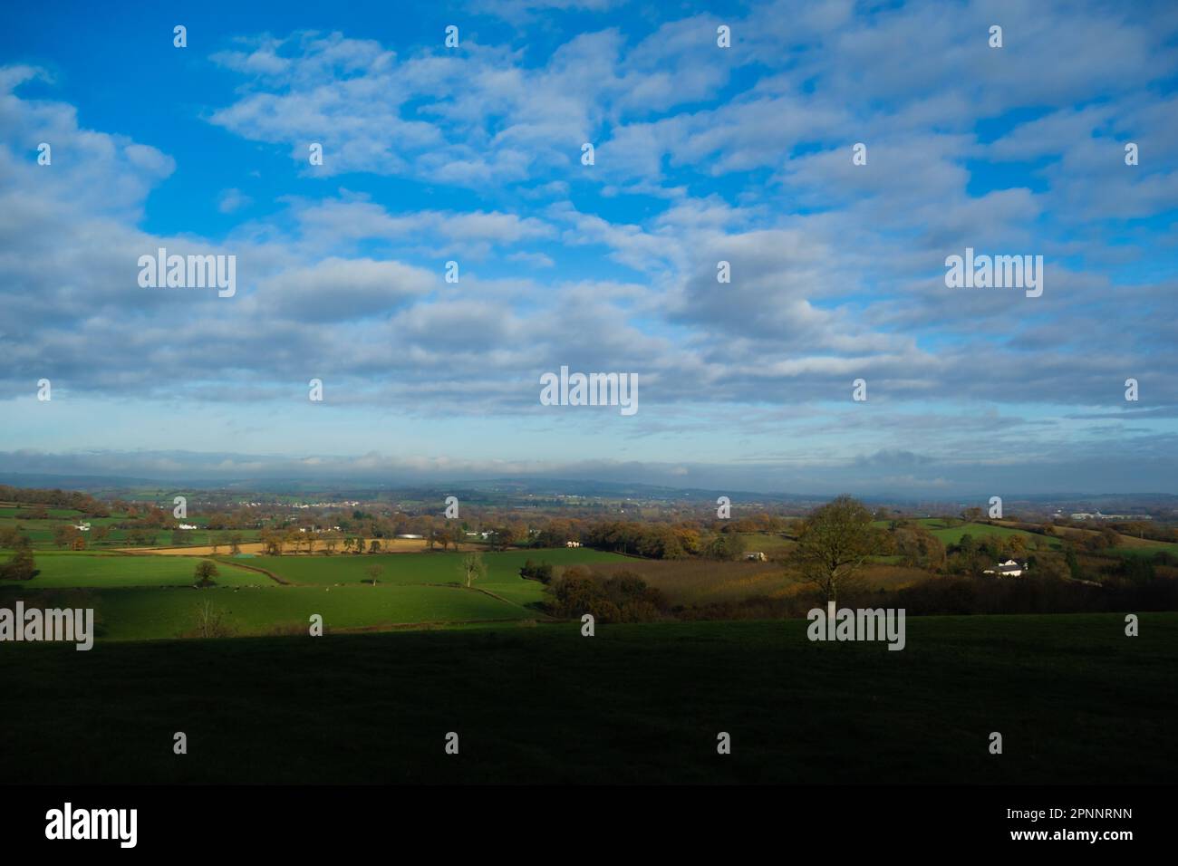 sunshine on Devon hills and fields with a slightly hazy and cloudy blue ...
